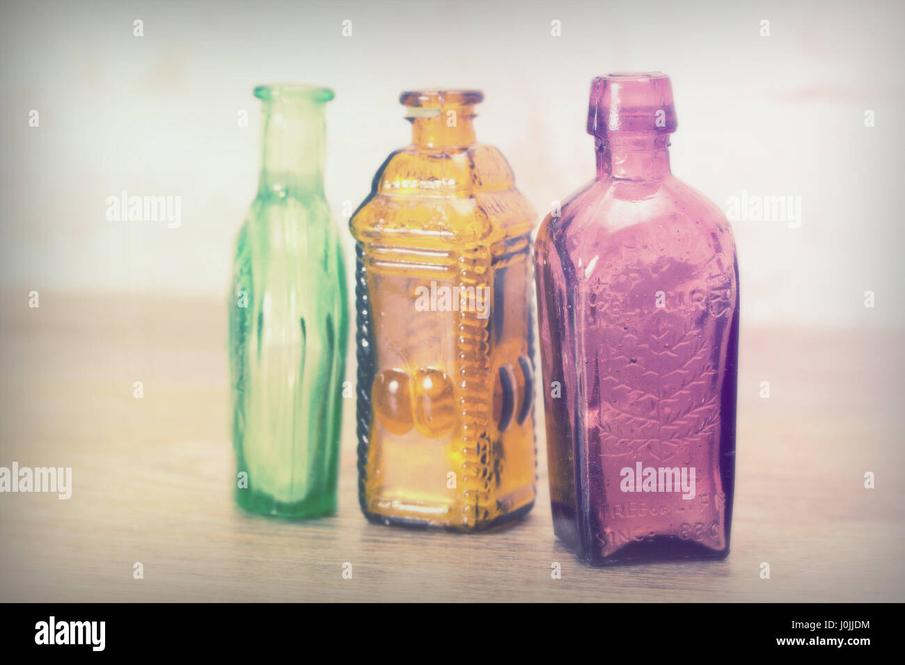 Selection of coloured glass bottles on a rustic background Stock Photo ...
