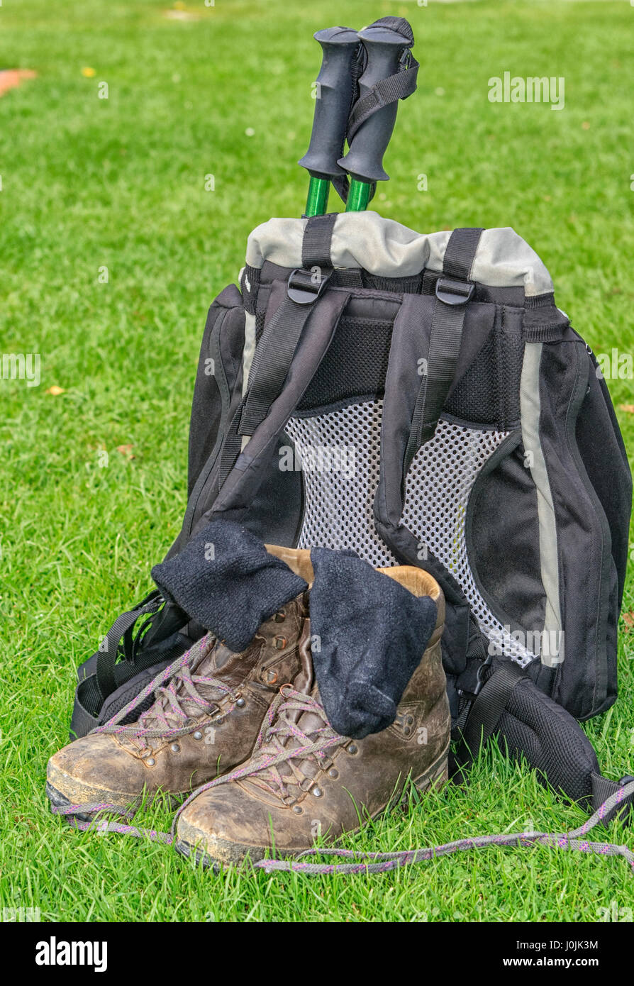 Backpack leaning against tree with hiking poles, hiking boots and socks ...