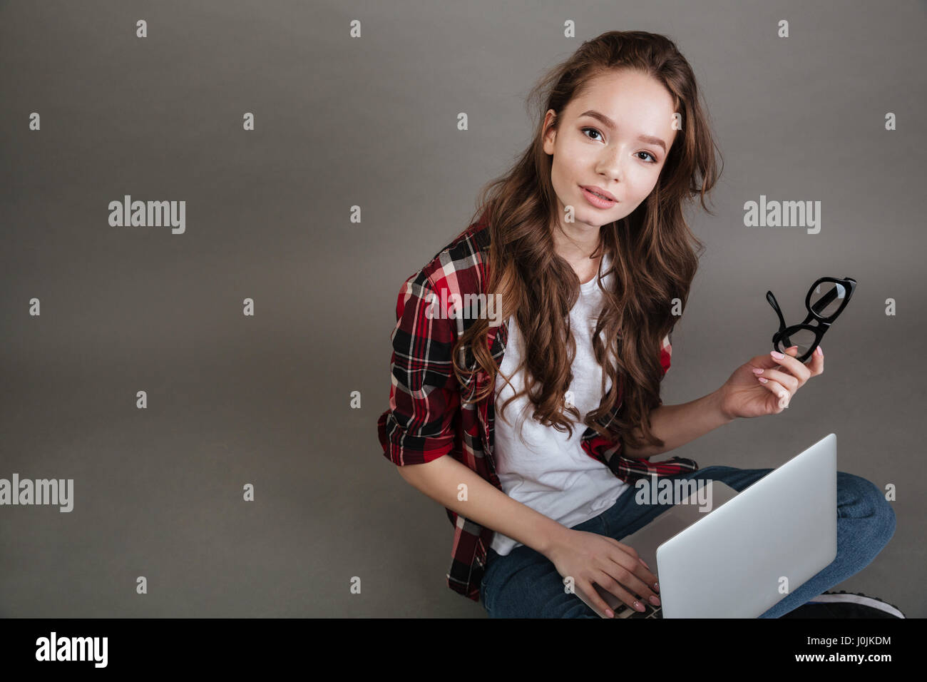 Image of beautiful young lady holding glasses sitting isolated over ...