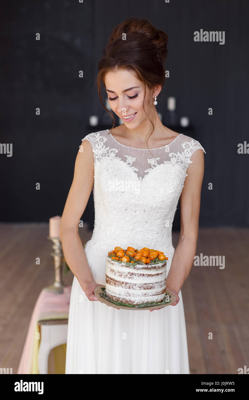 Beautiful bride holding a wedding cake and smiling. Vertical photo ...