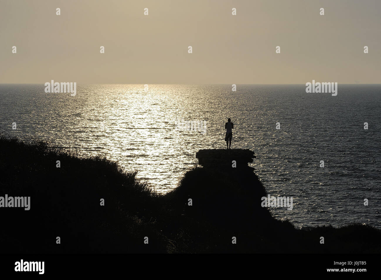 A young man stands on the remains of the Crusader wall above the sea at ...
