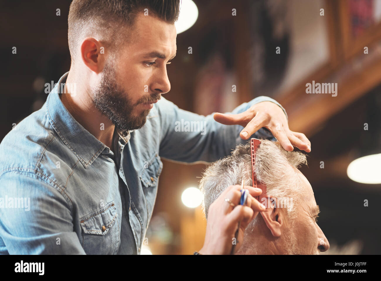 Capable master cutting hair of the client in the barbershop Stock Photo ...