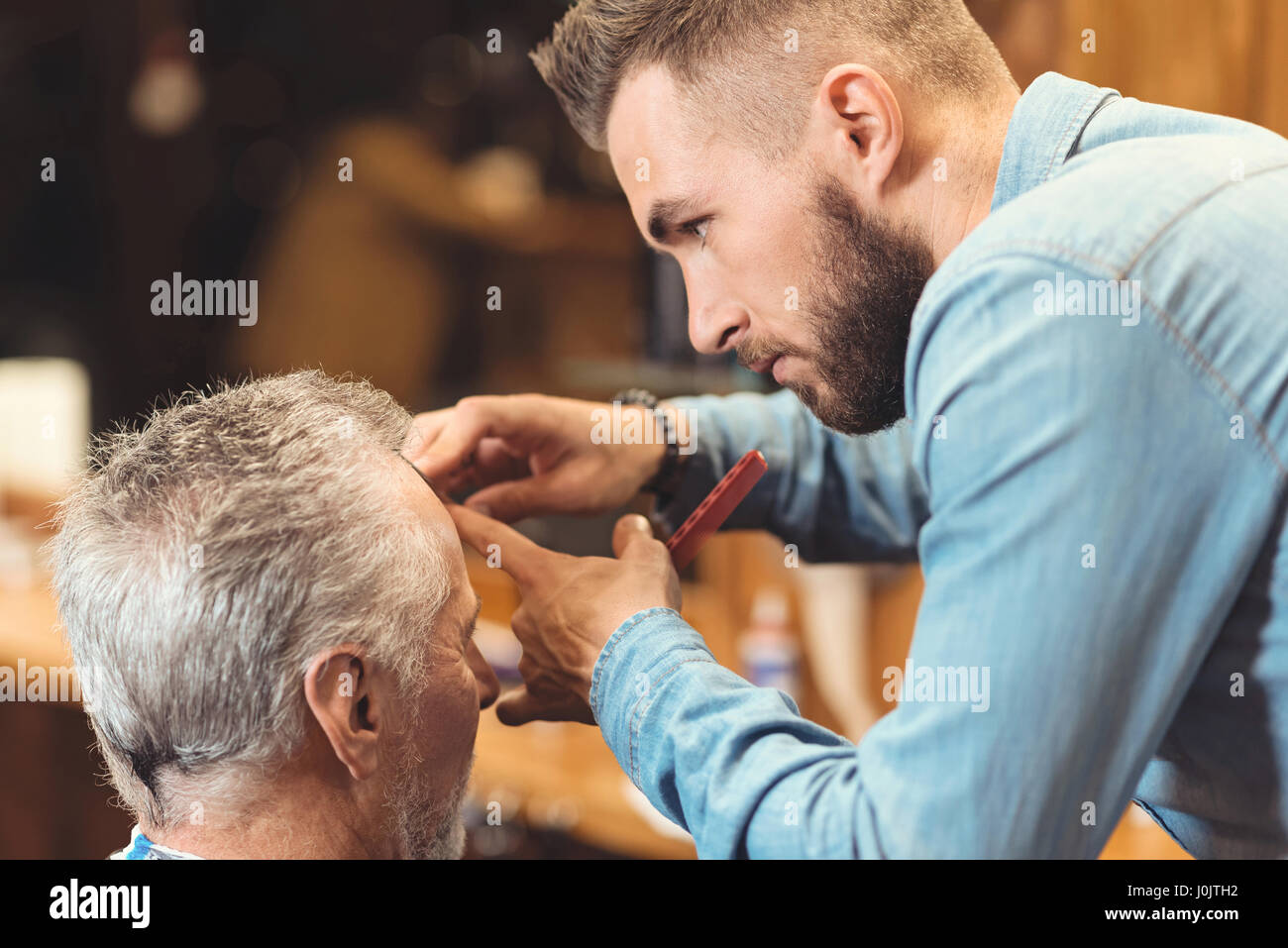 Professional barber making haircut of the aged client in barbershop ...