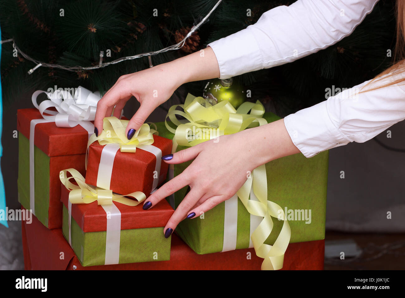 Beautiful girl in business attire sorting through presents under ...