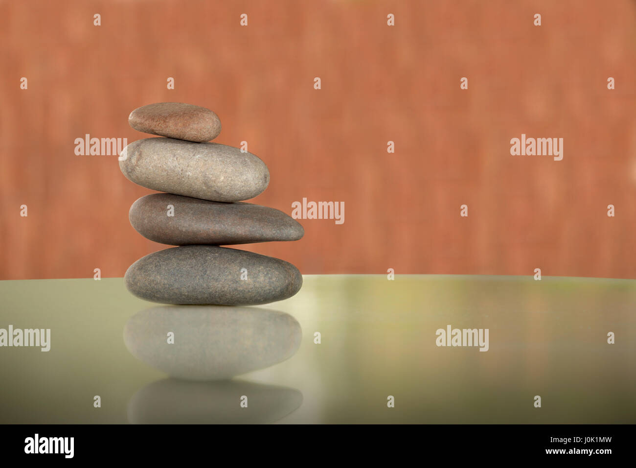 Four river rocks balanced on each other with salmon color background ...