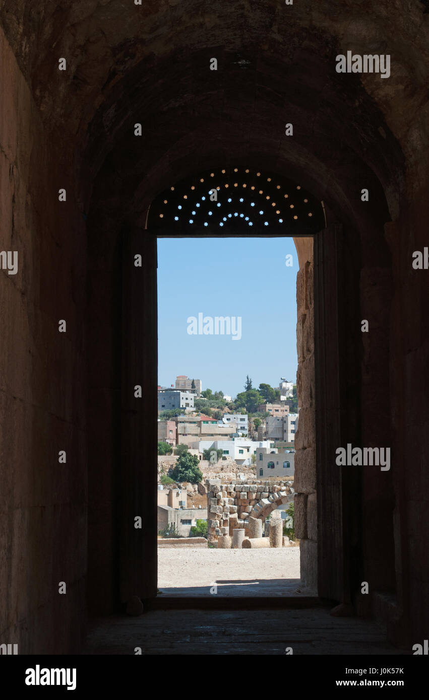 Skyline of modern Jerash seen through a decorated gate of the North ...