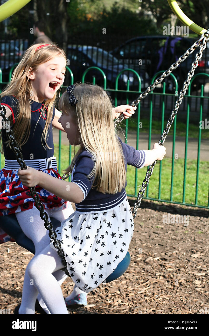 Children, kids having great fun playing on the swing, swings in the ...