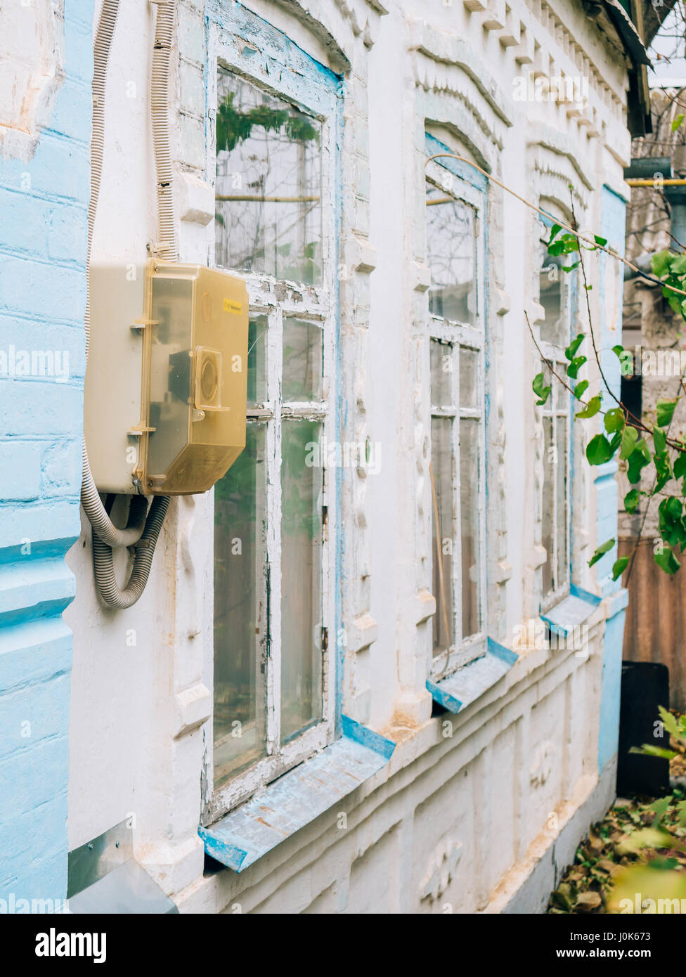 Electricity meter on the building. Old white-washed house in the ...