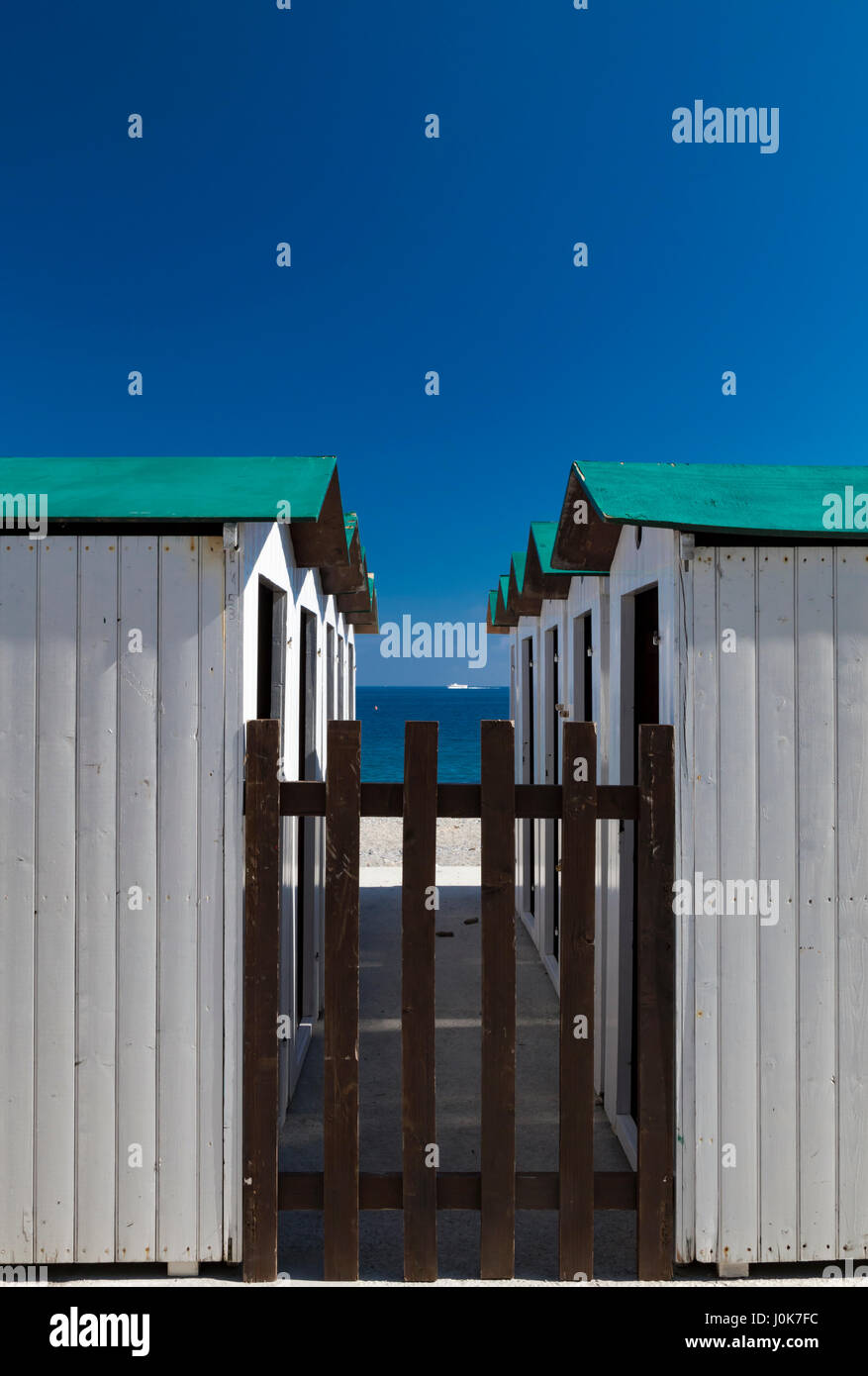 Summer concept with neat green and white beach huts behind a picket ...