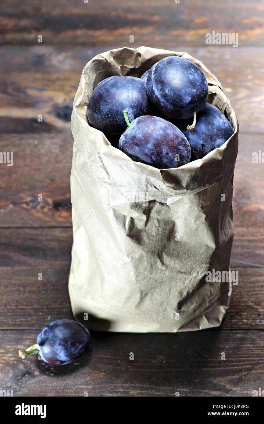 damson plums in a paper bag isolated on wooden background Stock Photo ...