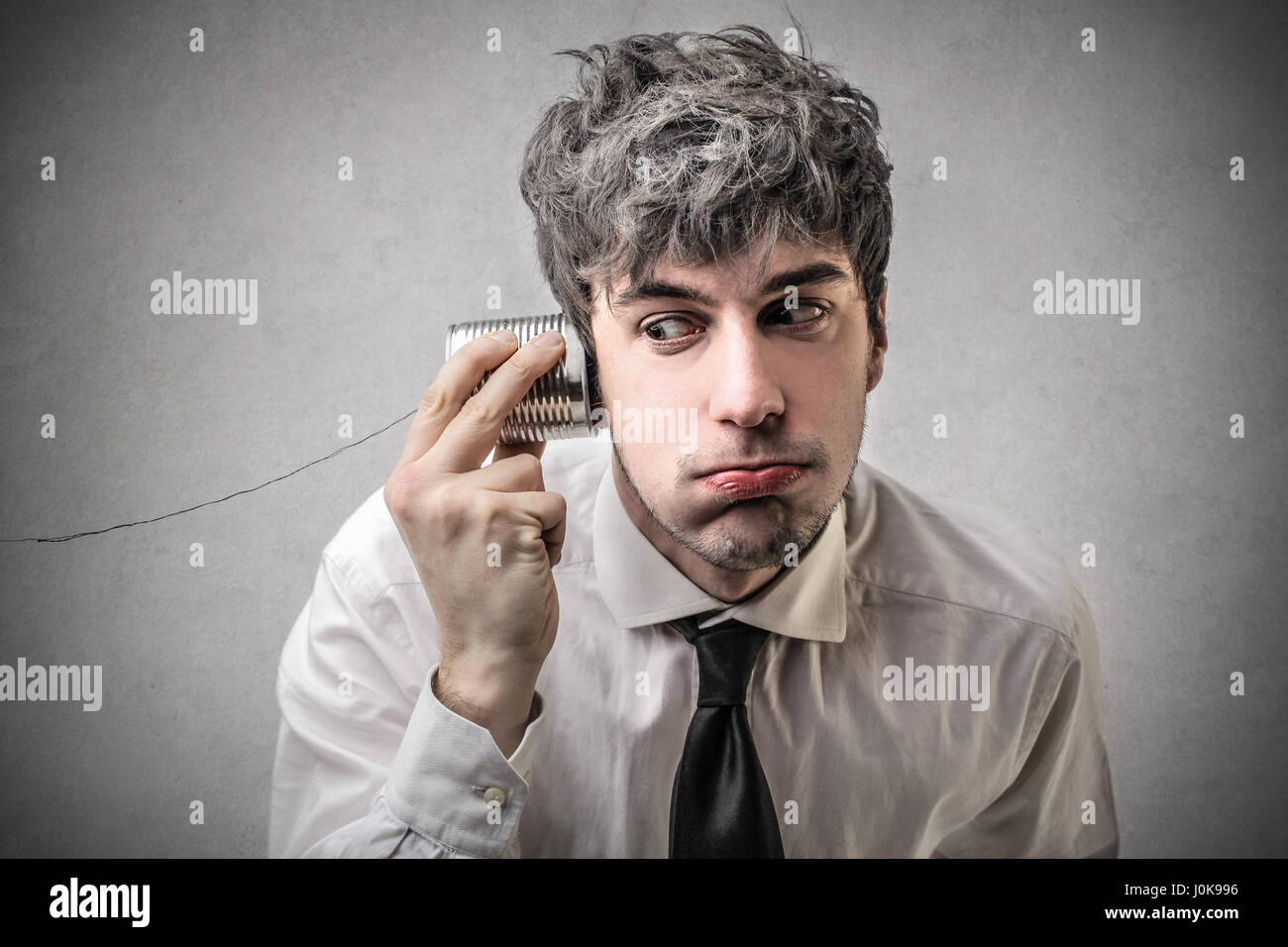 Bored businessman listening with can and rope Stock Photo - Alamy