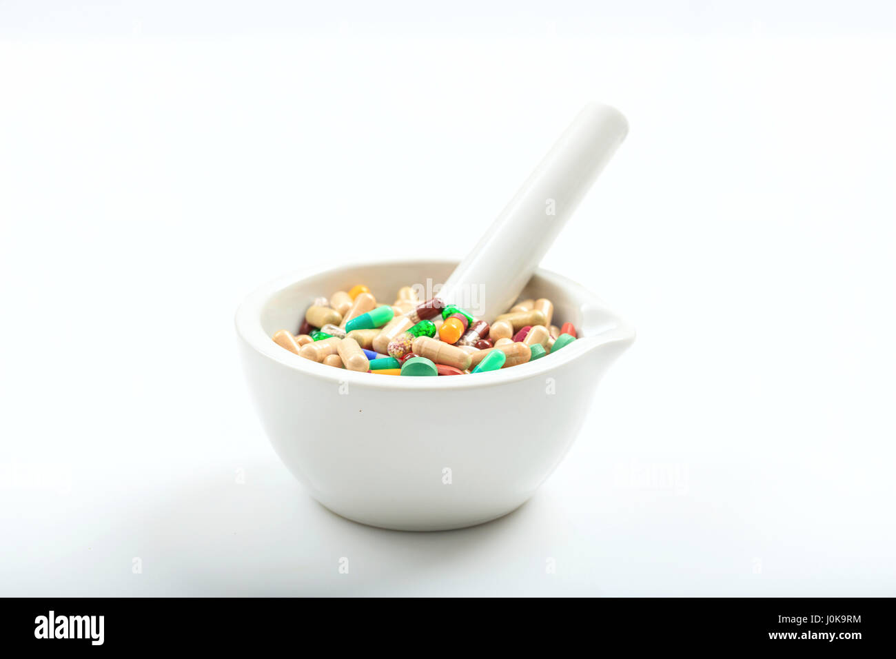 Pills in a pharmaceutical mortar on white background Stock Photo - Alamy