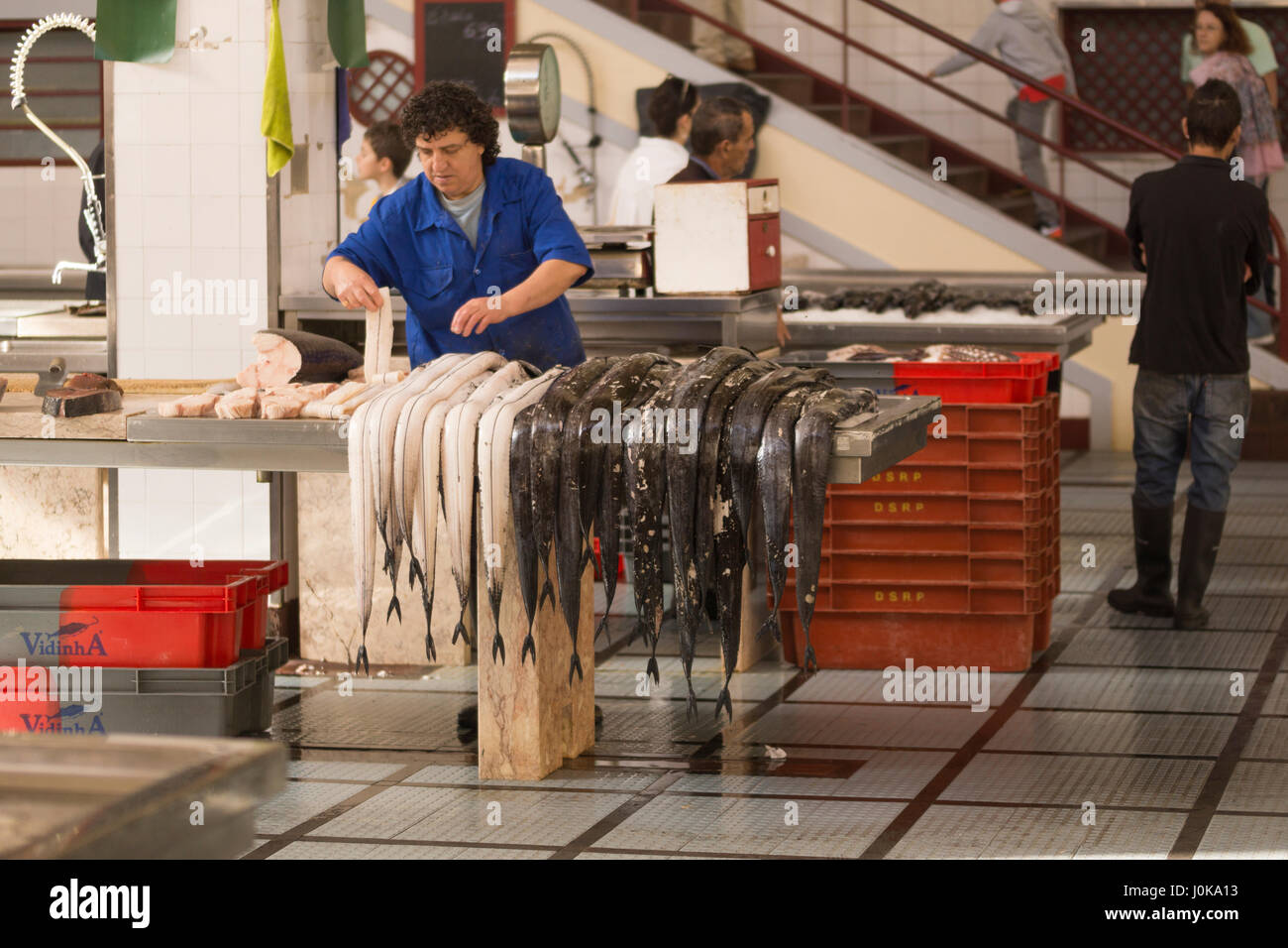 A fishmonger arranging black and white scabbardfish on his stall in ...