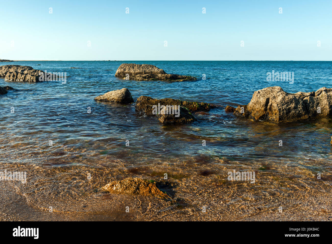 Coast with rocks and blue water Stock Photo - Alamy