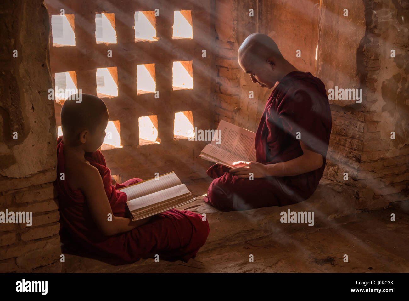 Two young monks studying in front of the window of the temple Stock ...