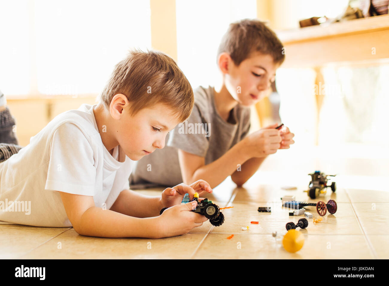 Two boys playing with lego at home with light from window background ...