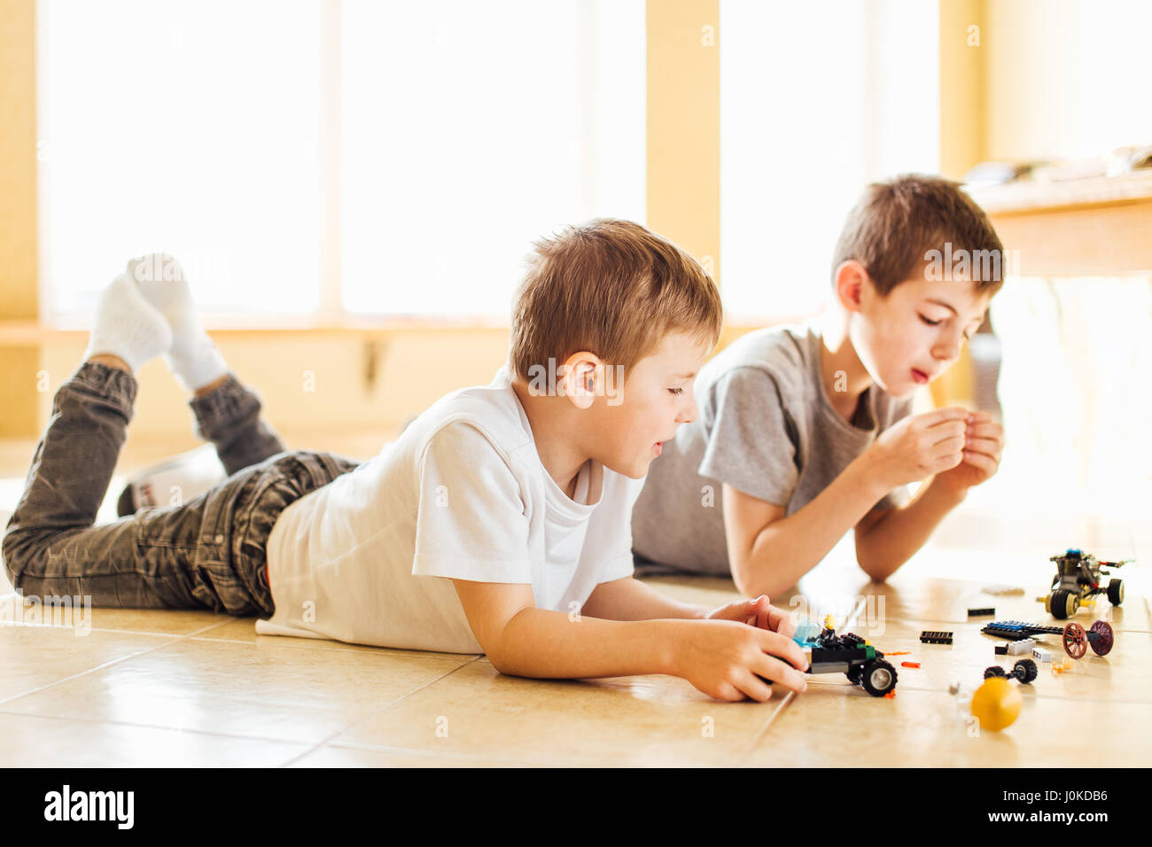 Two boys playing with lego at home with light from window background ...