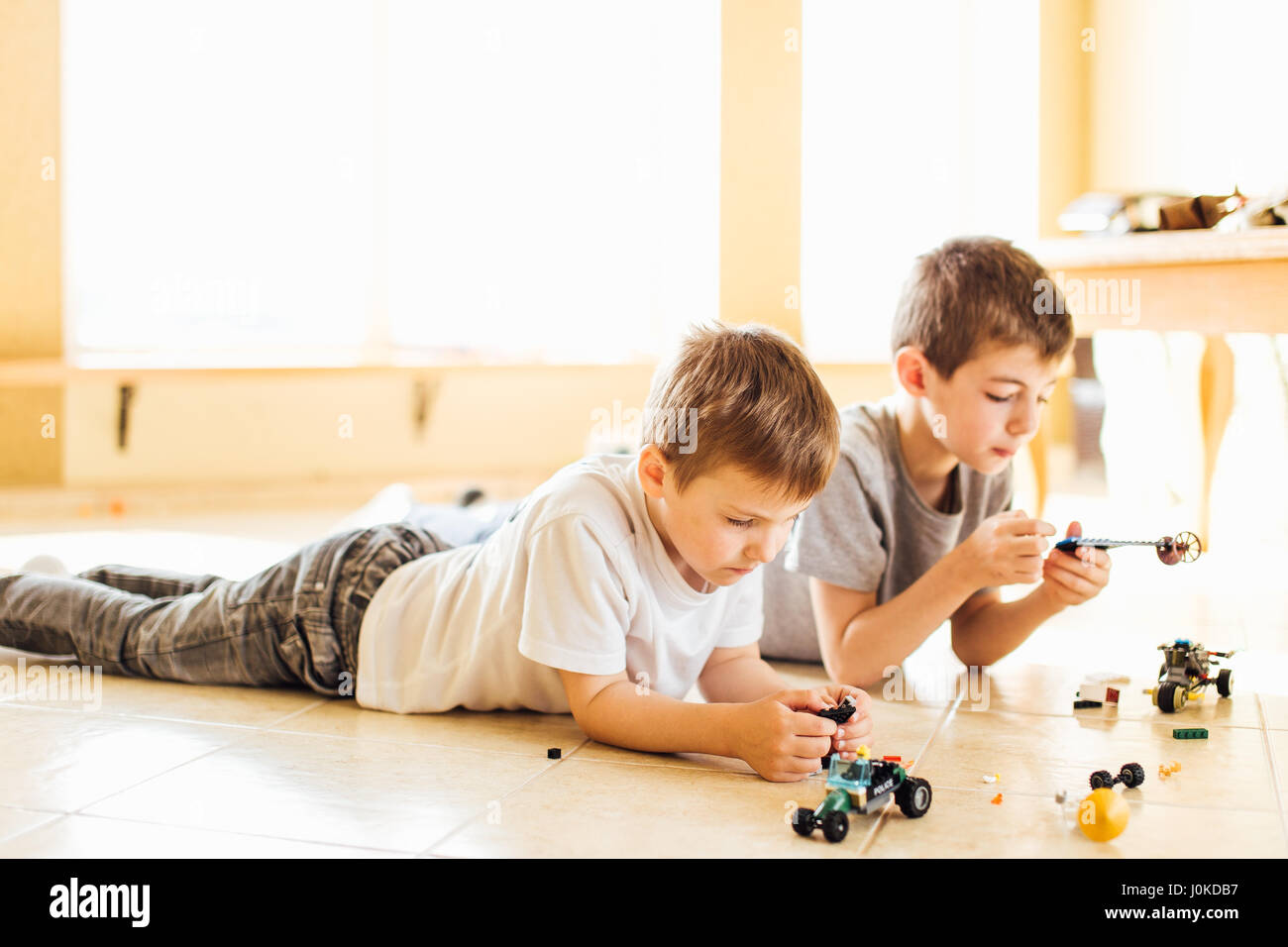 Two boys playing with lego at home with light from window background ...