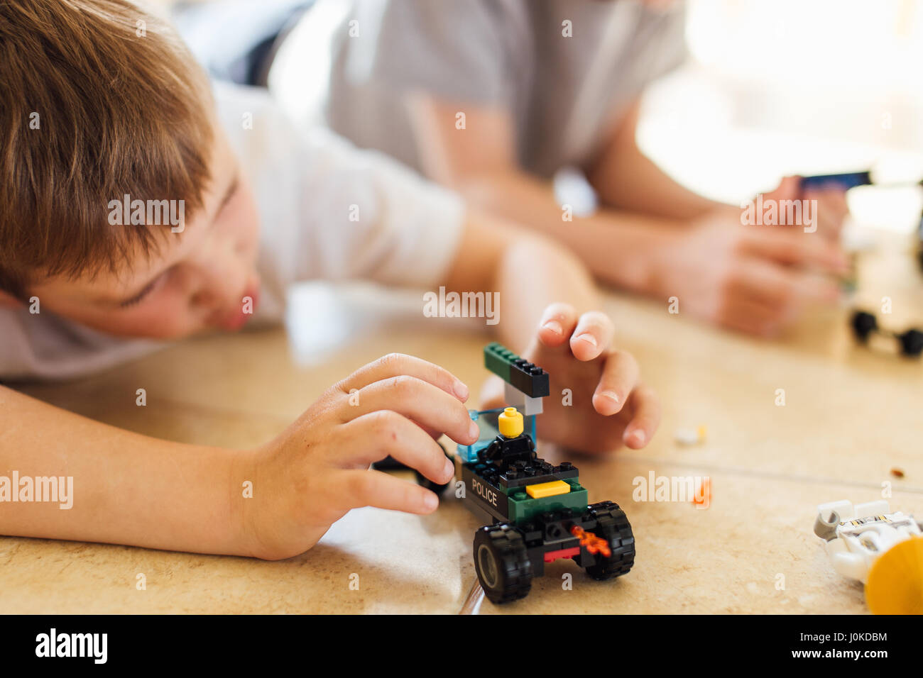 Two boys playing with lego at home with light from window background ...