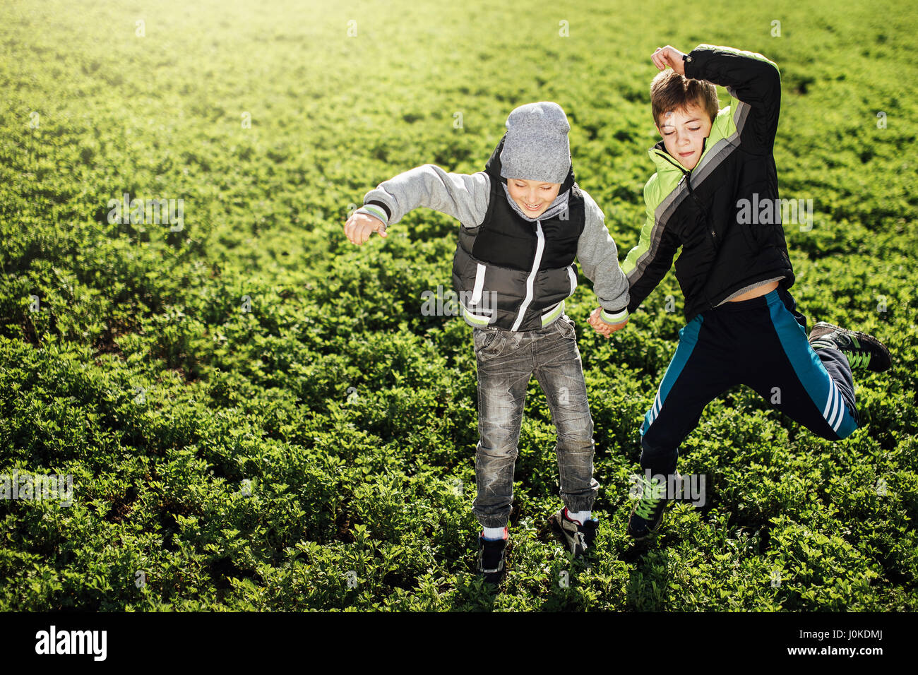 Two boys jumping on the field and smile Stock Photo - Alamy