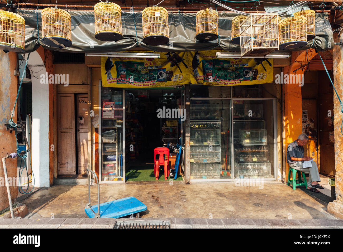 Kuala Lumpur, Malaysia - March 17, 2016: Birds vendor sitting before ...