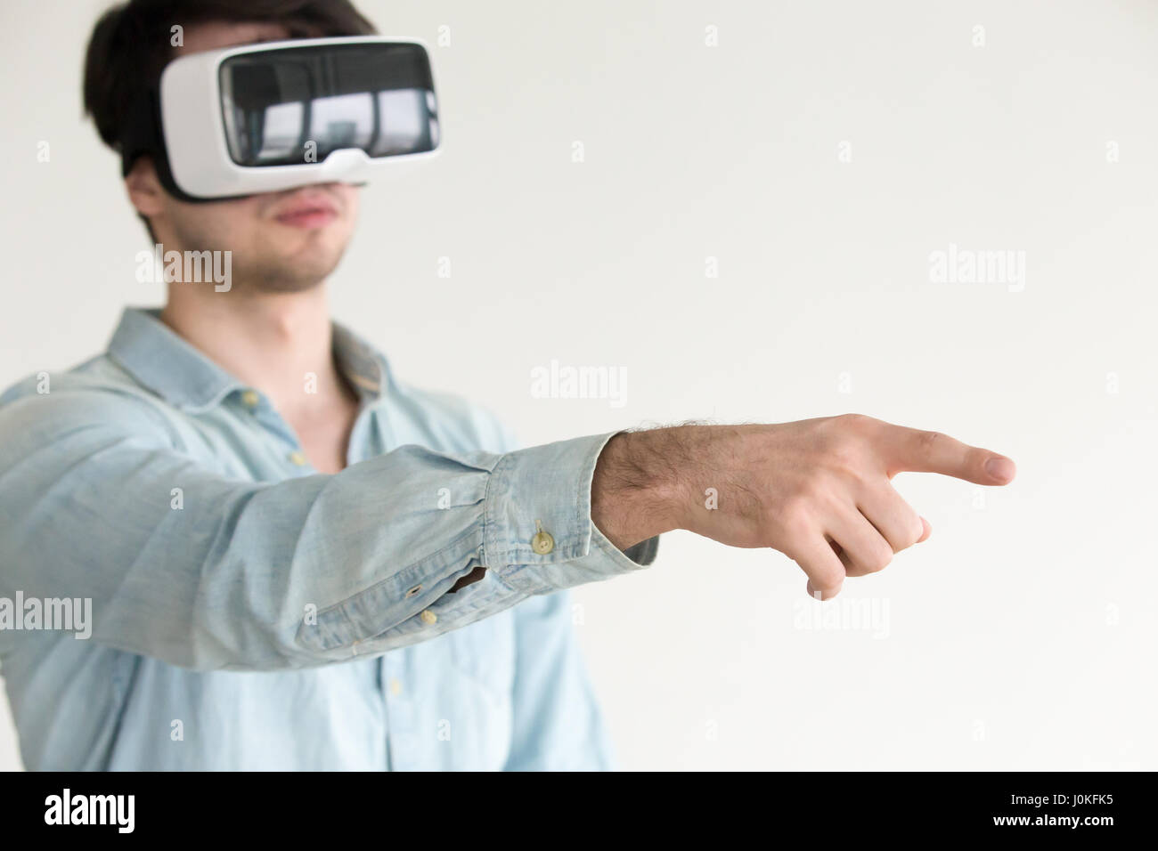 Young man wearing vr helmet showing or touching virtual objects Stock ...
