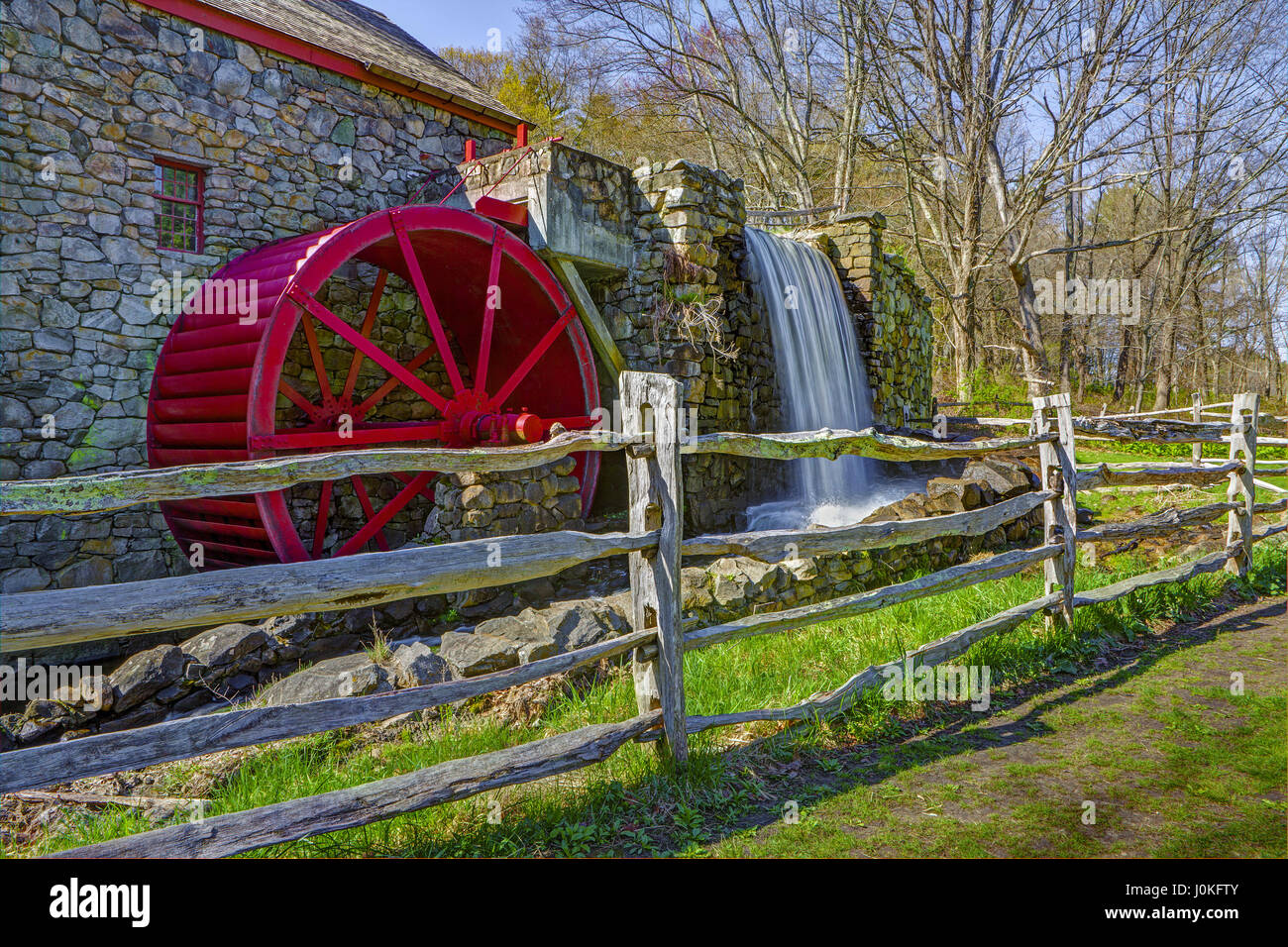 Red metal water wheel and waterfall headrace of the Old Grist Mill in ...
