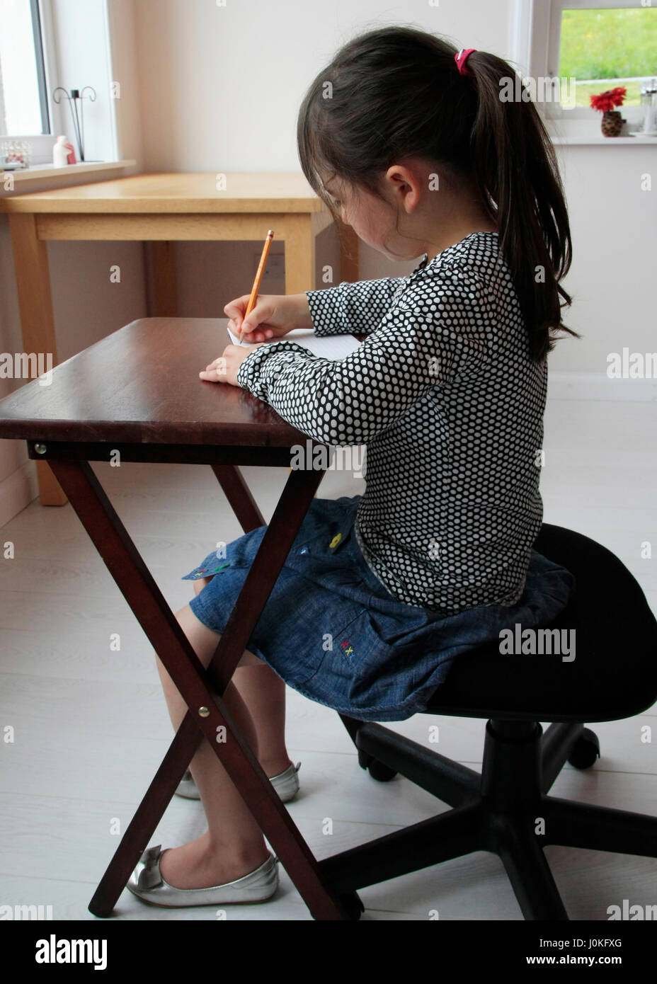 Young girl writing a letter at a table Stock Photo - Alamy