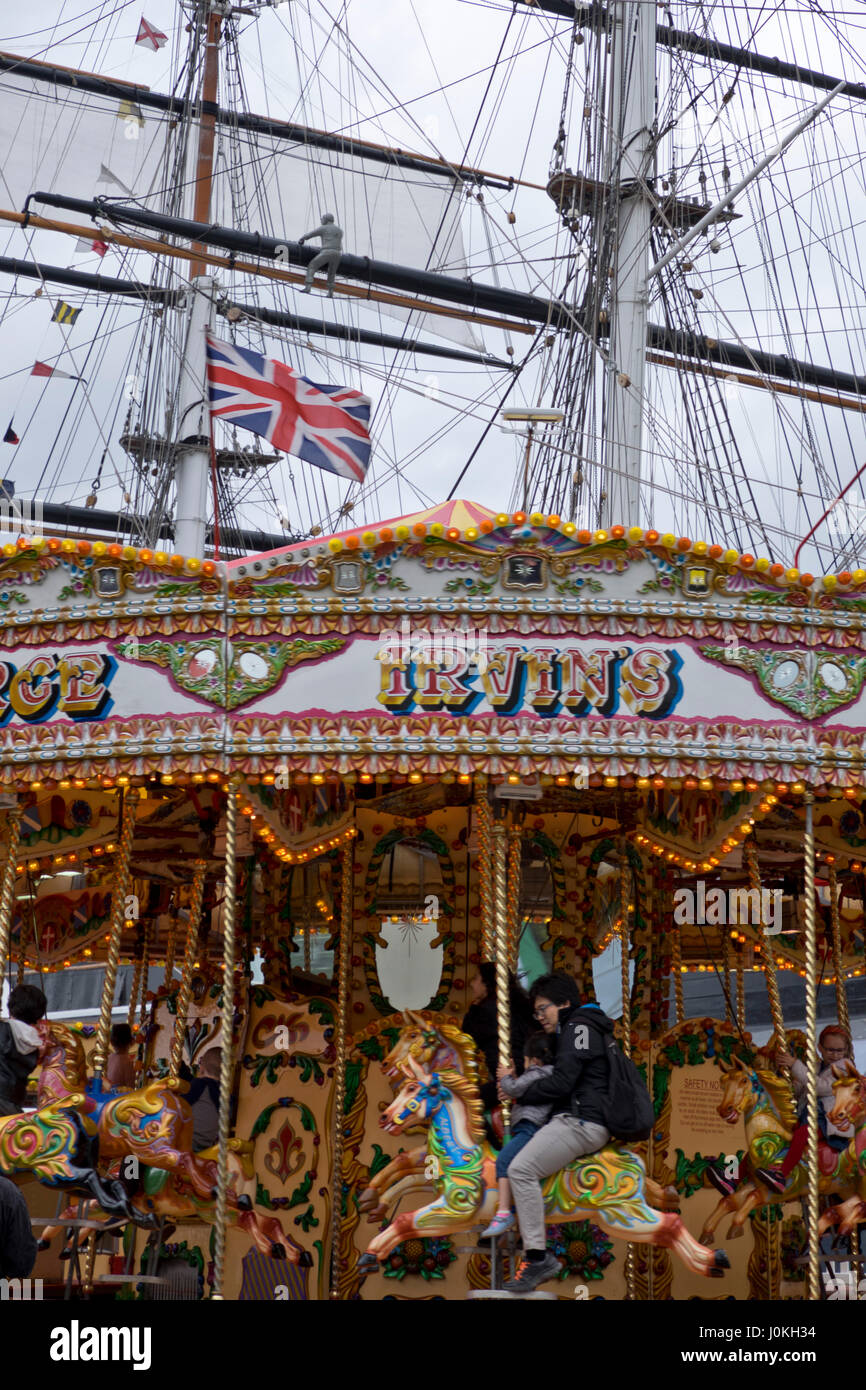 Tourists at merry-go-round with Cutty Sark in background during ...