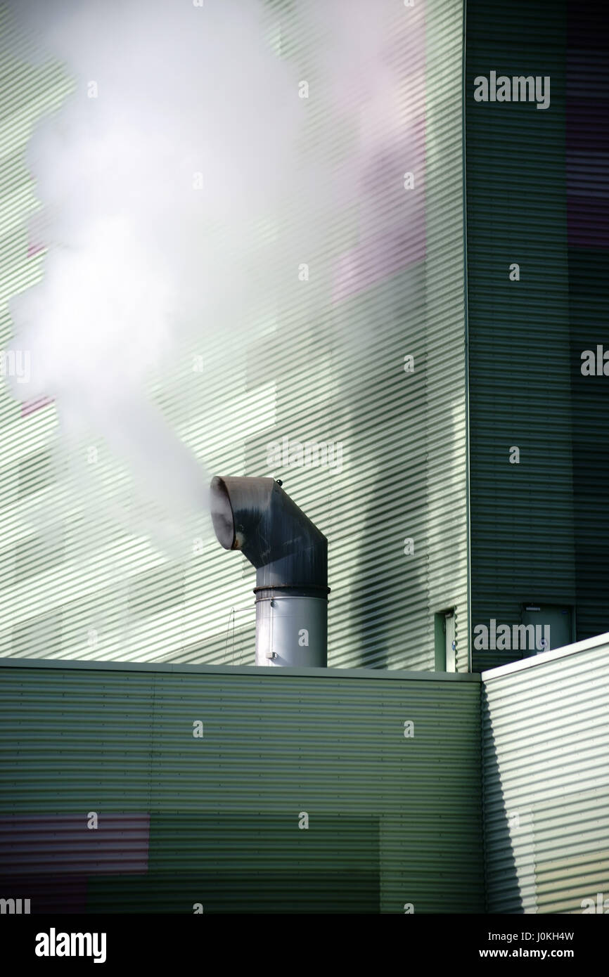 The smoky chimney of an industrial plant on the outside wall of a power ...