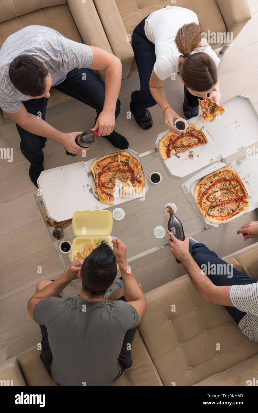 a group of young people cheerfully spending time while eating pizza in ...