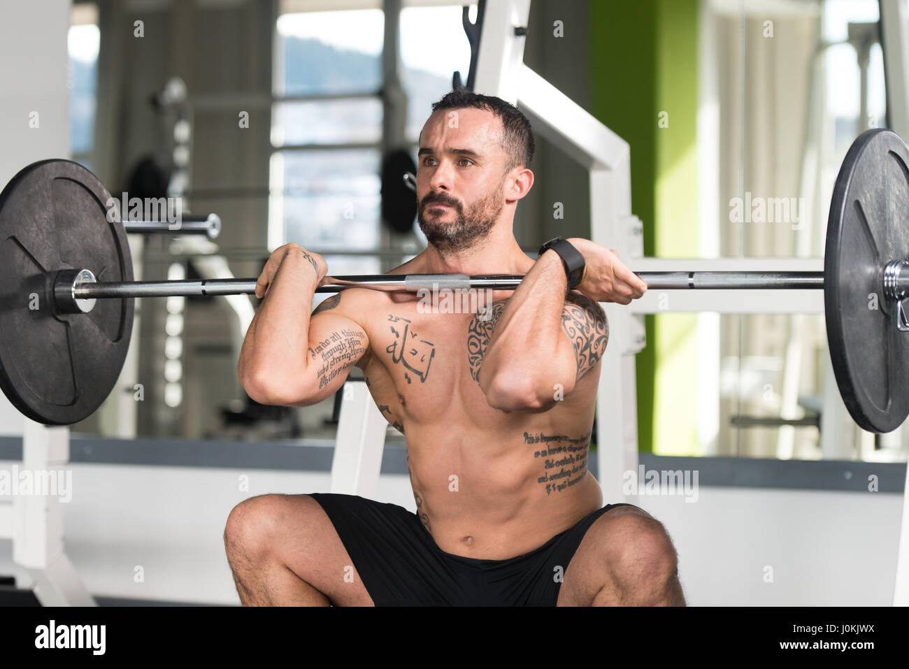 Healthy Fitness Man Working Out Legs With Barbell In A Gym - Front ...