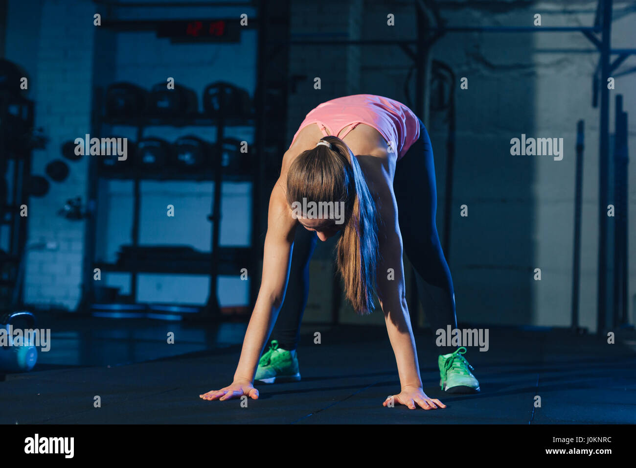Fit woman in colourful sportswear doing burpees on a exercise mat in a ...