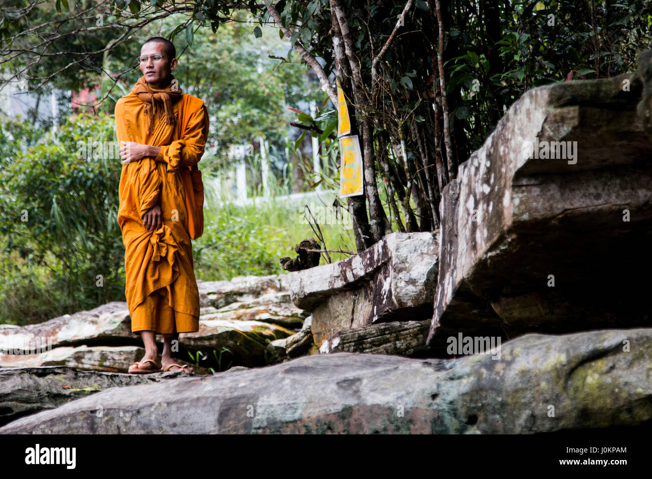 A monk watching out at a waterfall in a national park in Cambodia Stock ...
