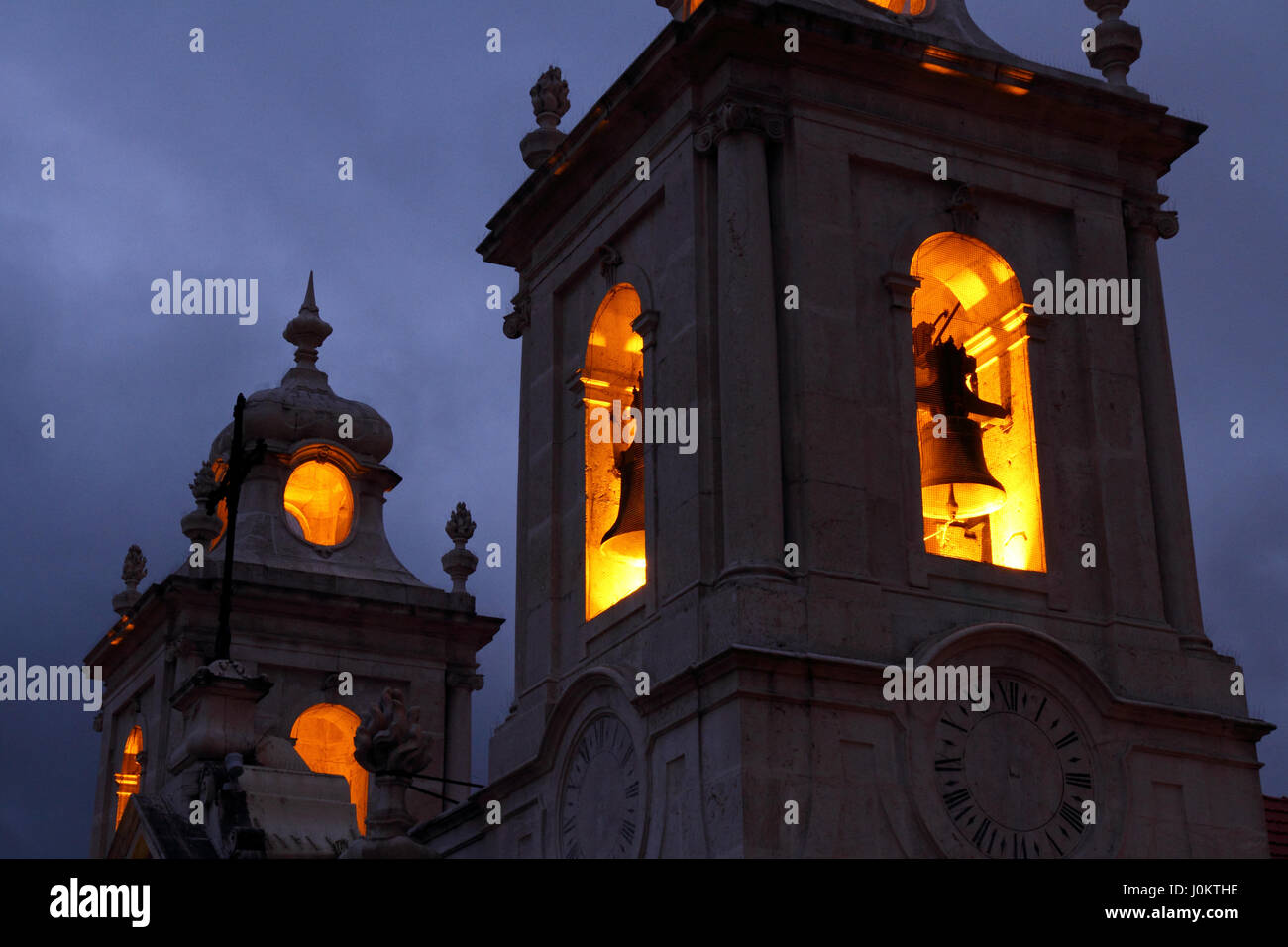 A spooky and dark church bell tower with the bells lit up by lights on ...