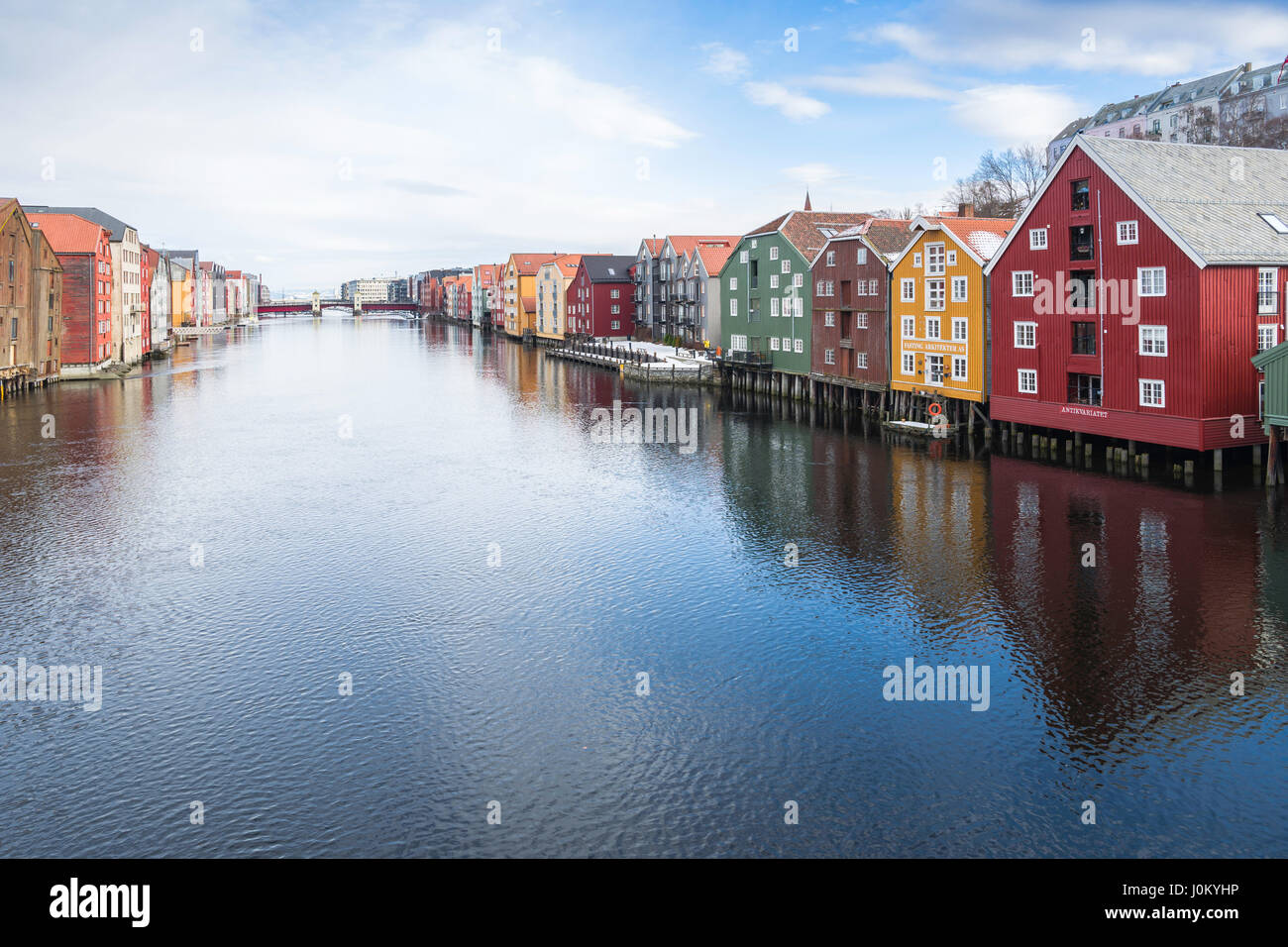 Traditional warehouses line the sides of the Nidelva River as it flows ...