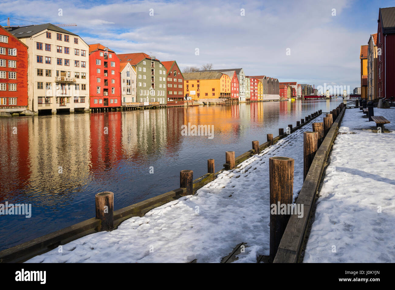 Traditional warehouses line the sides of the Nidelva River as it flows ...