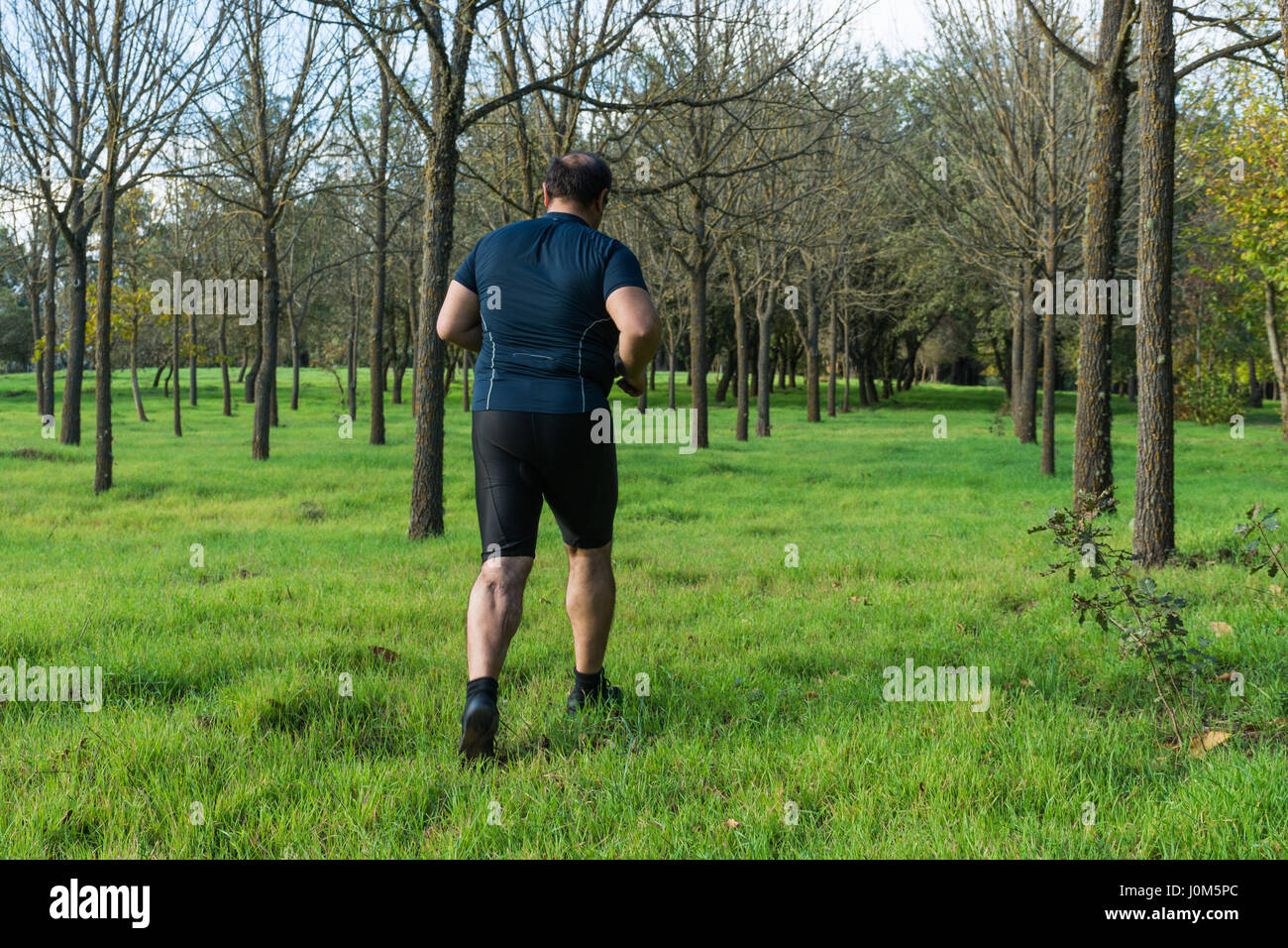 Big belly man jogging , exercising, doing cardio in the park , slightly ...