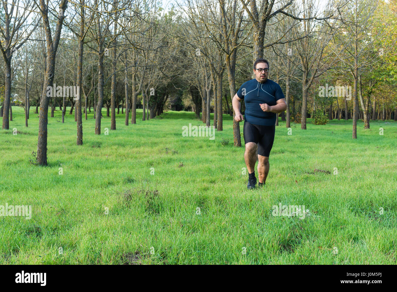 Big belly man jogging , exercising, doing cardio in the park , slightly ...