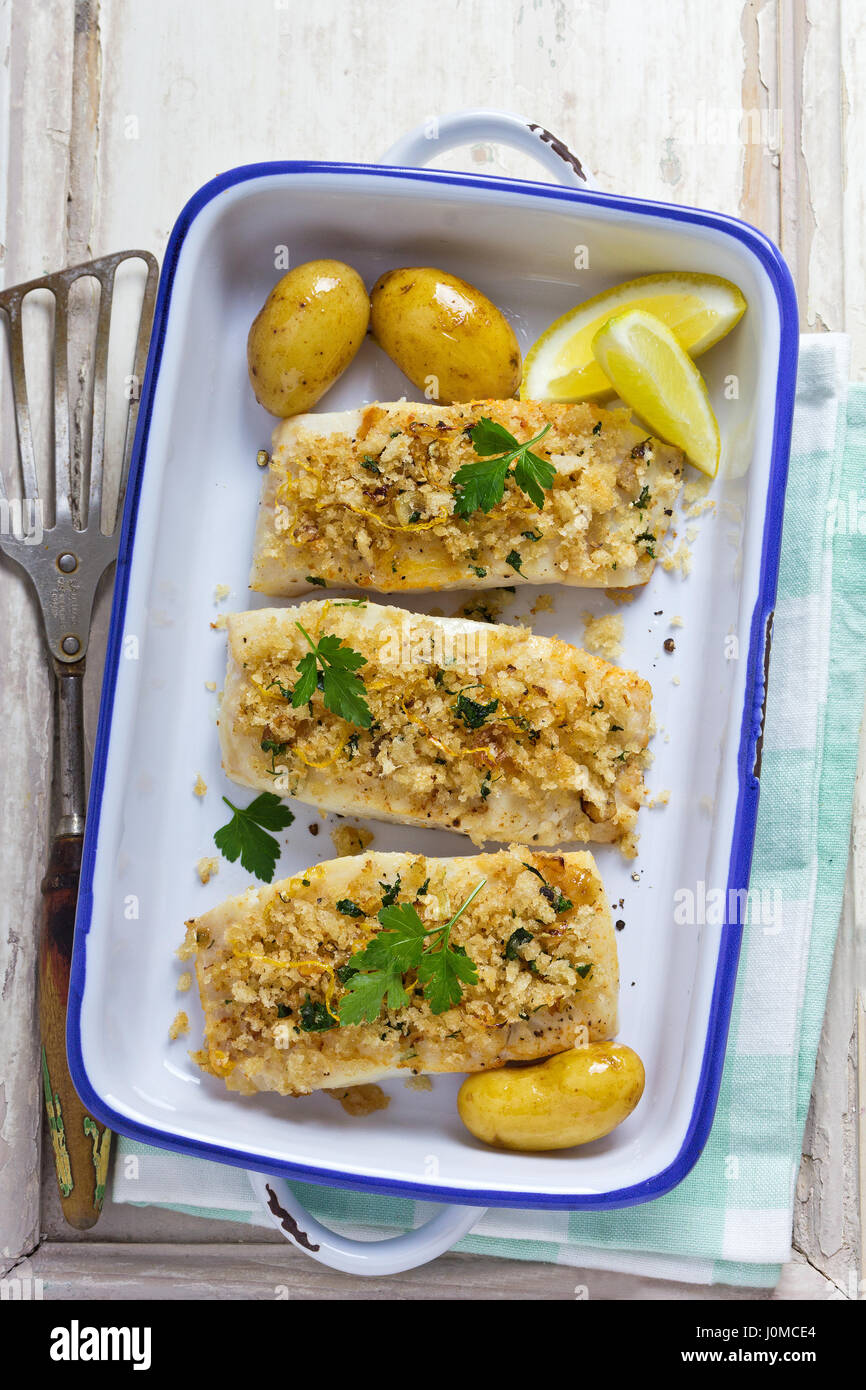 Baked cod with breadcrumbs and herbs, served with baby potatoes Stock ...