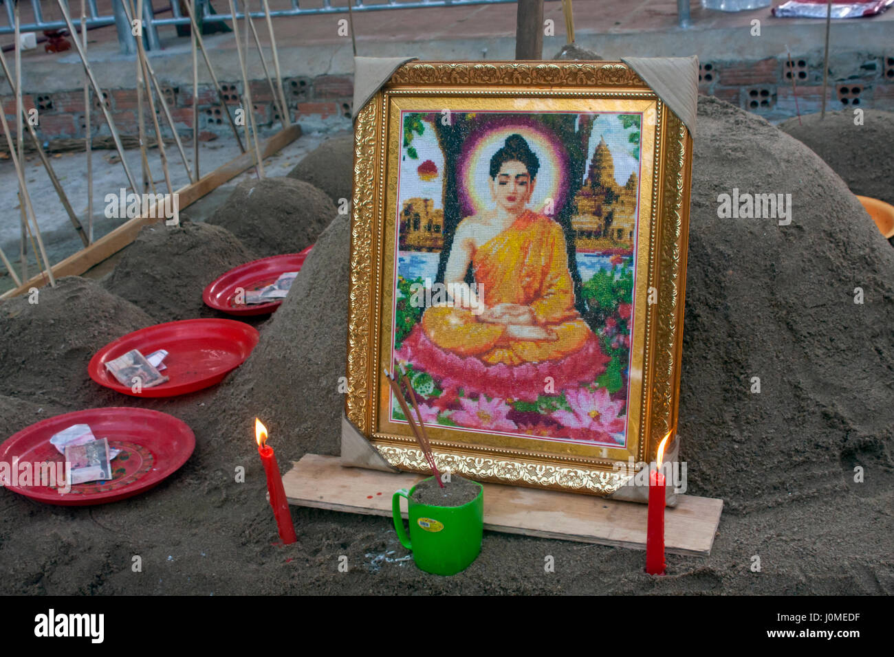 Plates containing money rest adjacent to a Buddhist tapestry during a ...