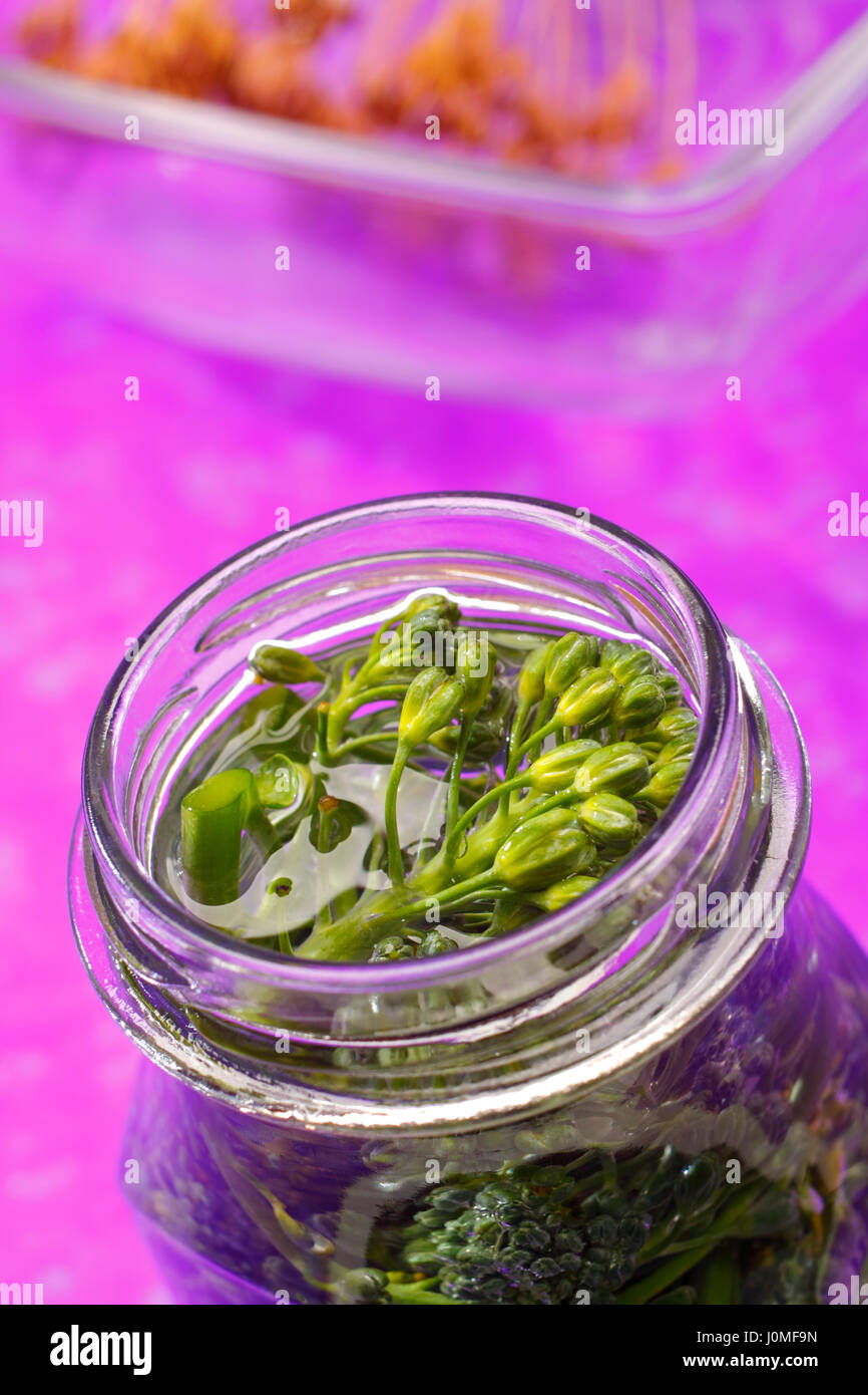 Small pickled broccoli parts in opened jar with unfocused background ...