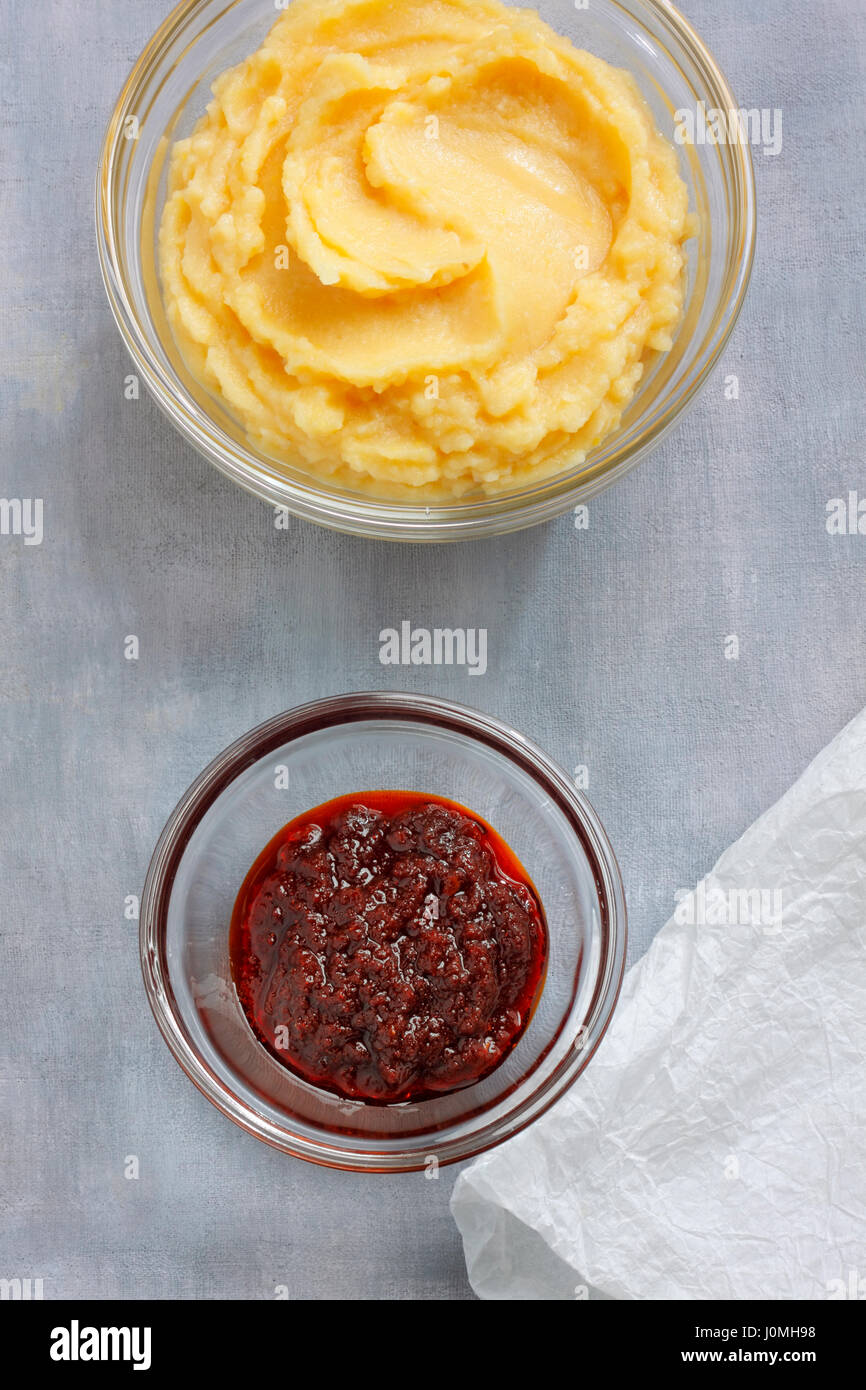 Hummus and harissa sauce in glass bowls on gray painted textile ...