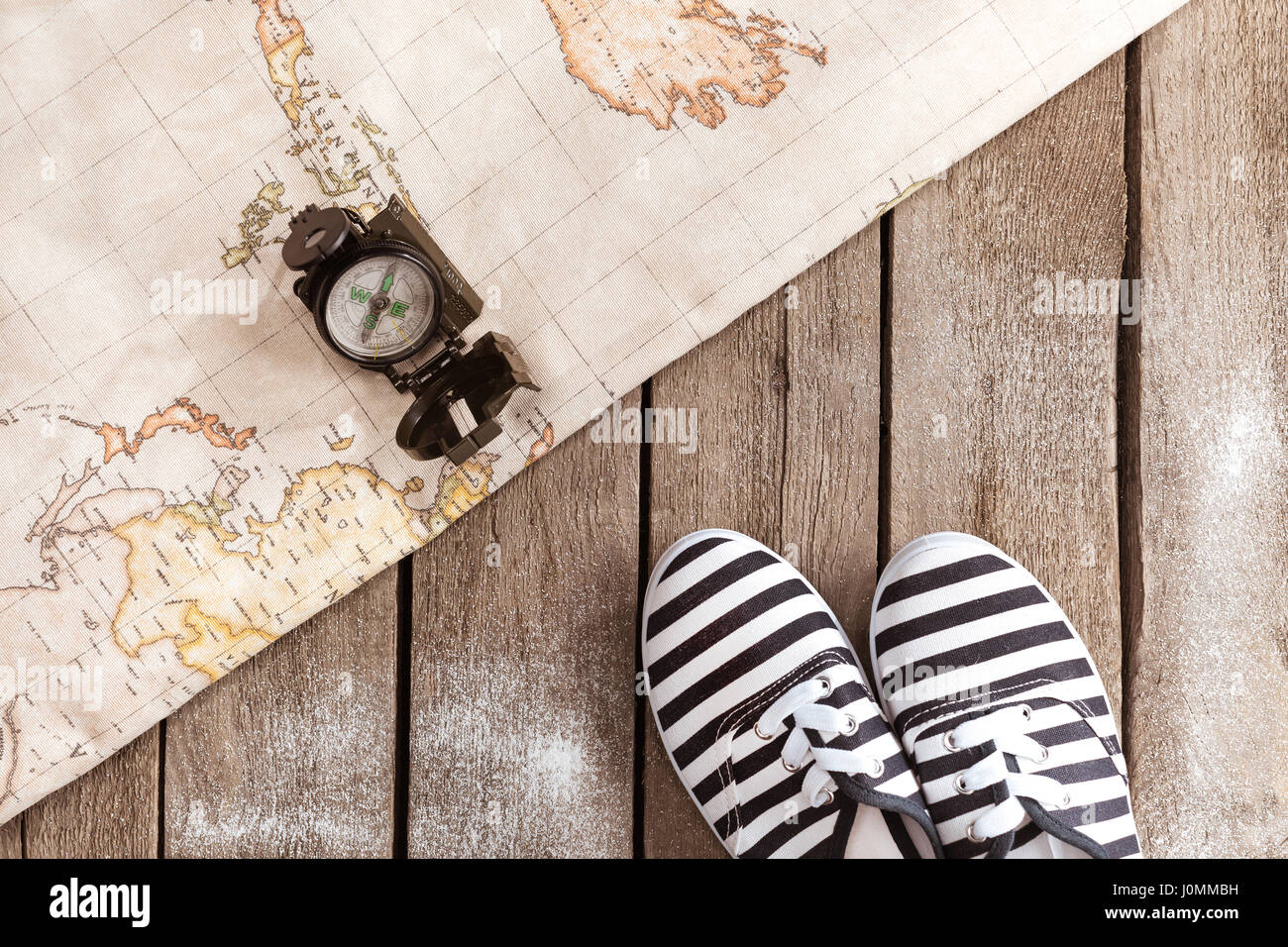 Top view of compass, world map and striped shoes on wooden table ...