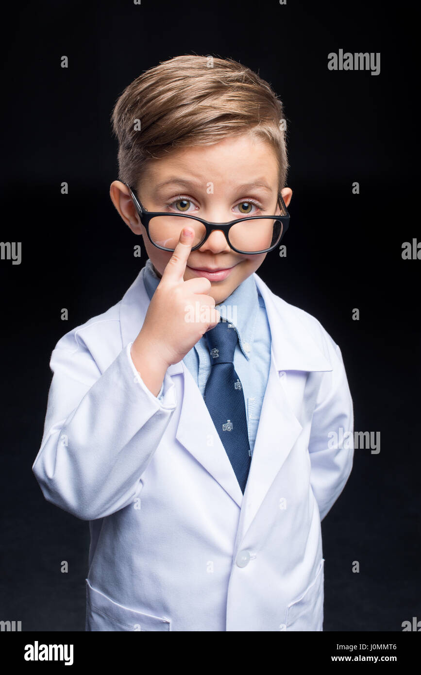 Little boy scientist in lab coat adjusting eyeglasses on black Stock ...