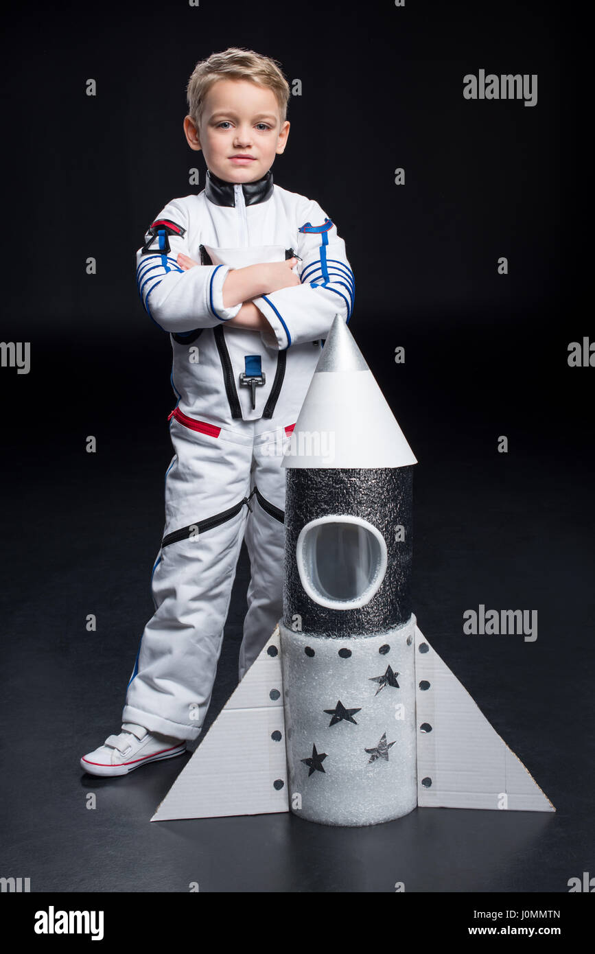 Confident little boy astronaut in space suit standing with crossed arms ...
