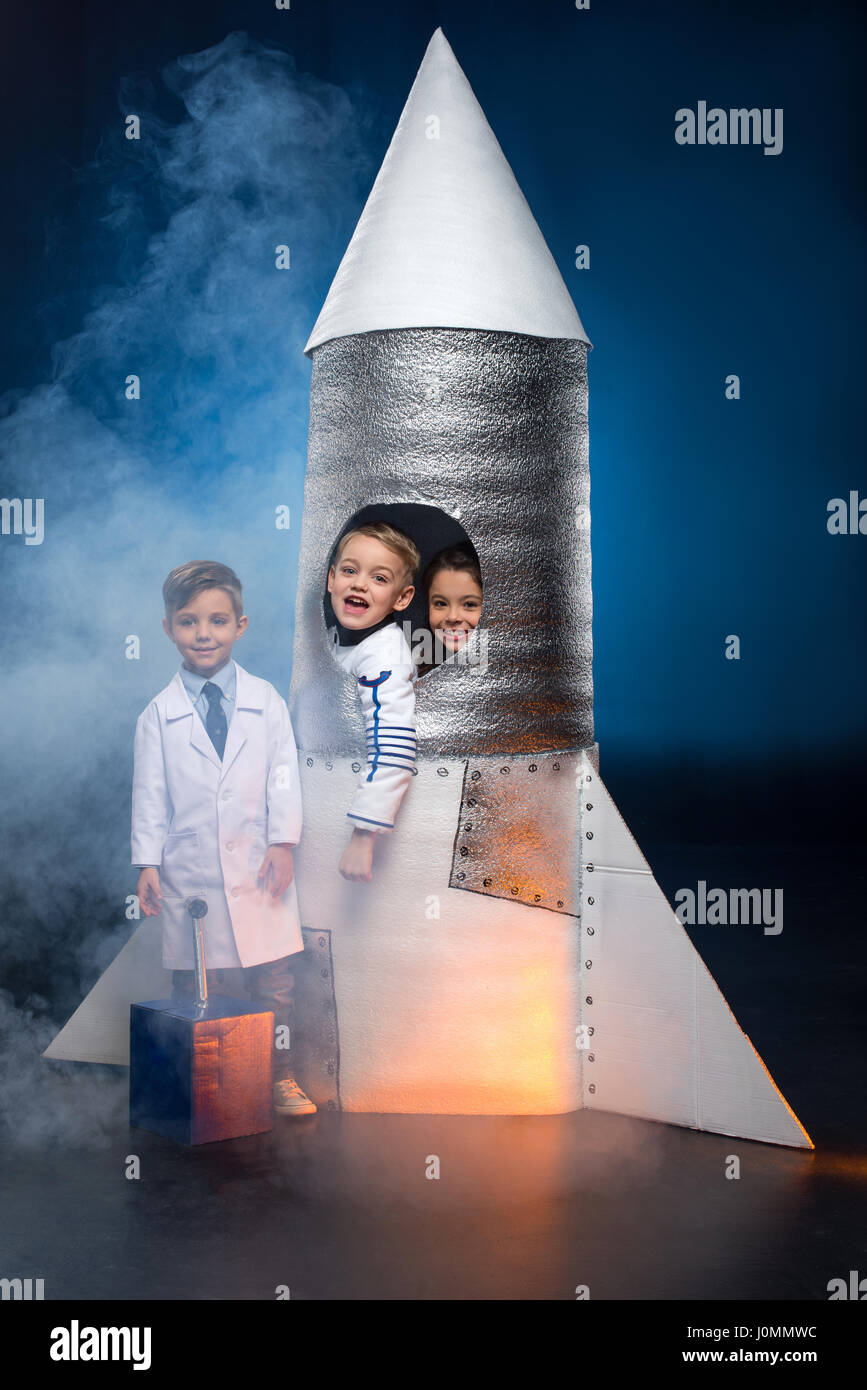 Three adorable little kids playing astronauts and launching spaceship ...