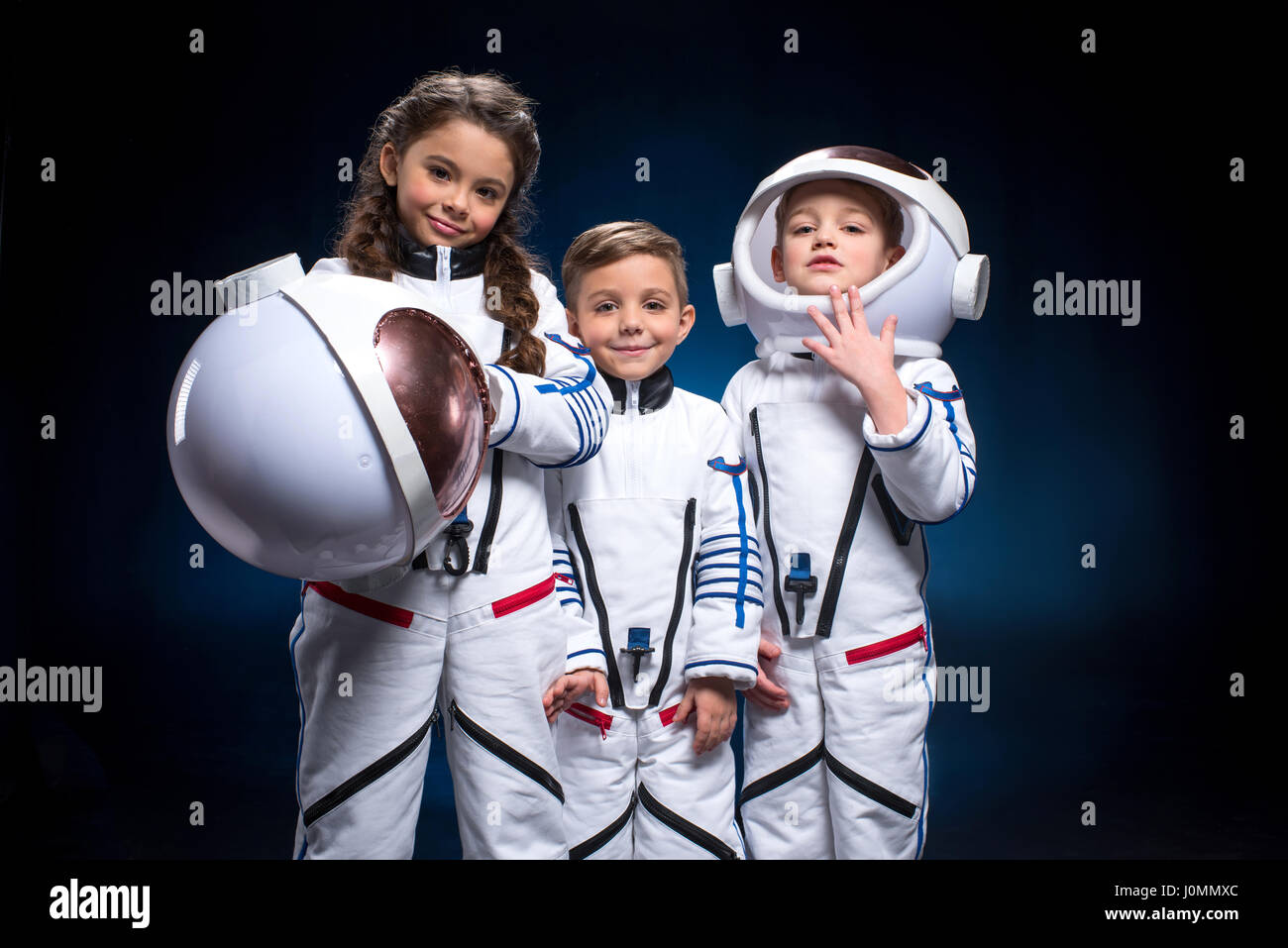 Two little boys and girl in space suits playing astronauts looking at ...