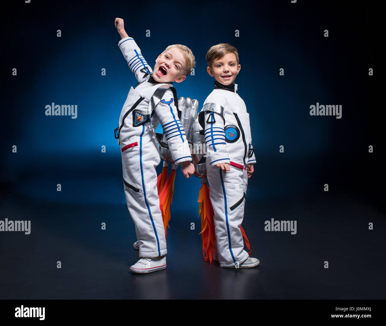 Two cute little boys in space suits standing back to back looking at ...