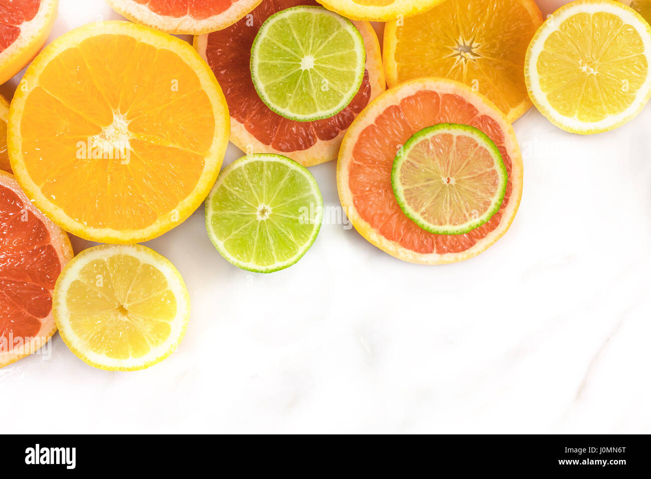 Vibrant juicy citrus fruits on a white marble texture with copy space ...